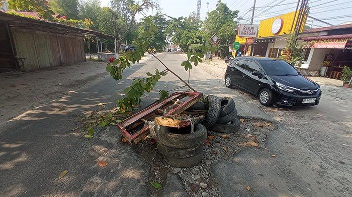 Warga Letak Ban Bekas dan Dahan Pohon di Jalan Rajawali yang Berlubang, Membahayakan Pengendara ...