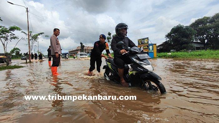 FOTO : Anggota Brimob Polda Riau Bantu Dorong Kendaraan yang Mogok Saat Lewati Banjir ...